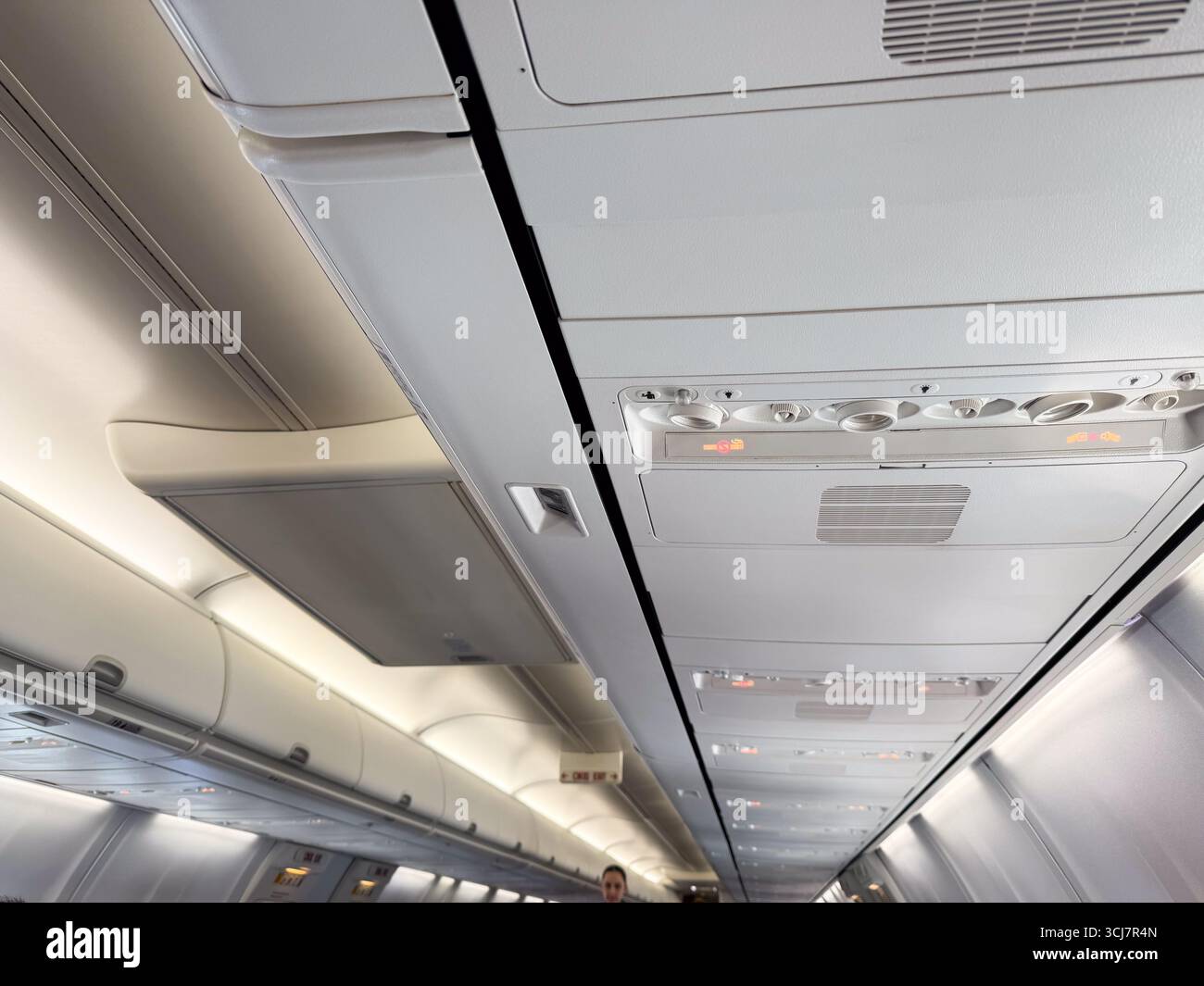 An airplane cabin ceiling with air vents, signs, and compartments above ...
