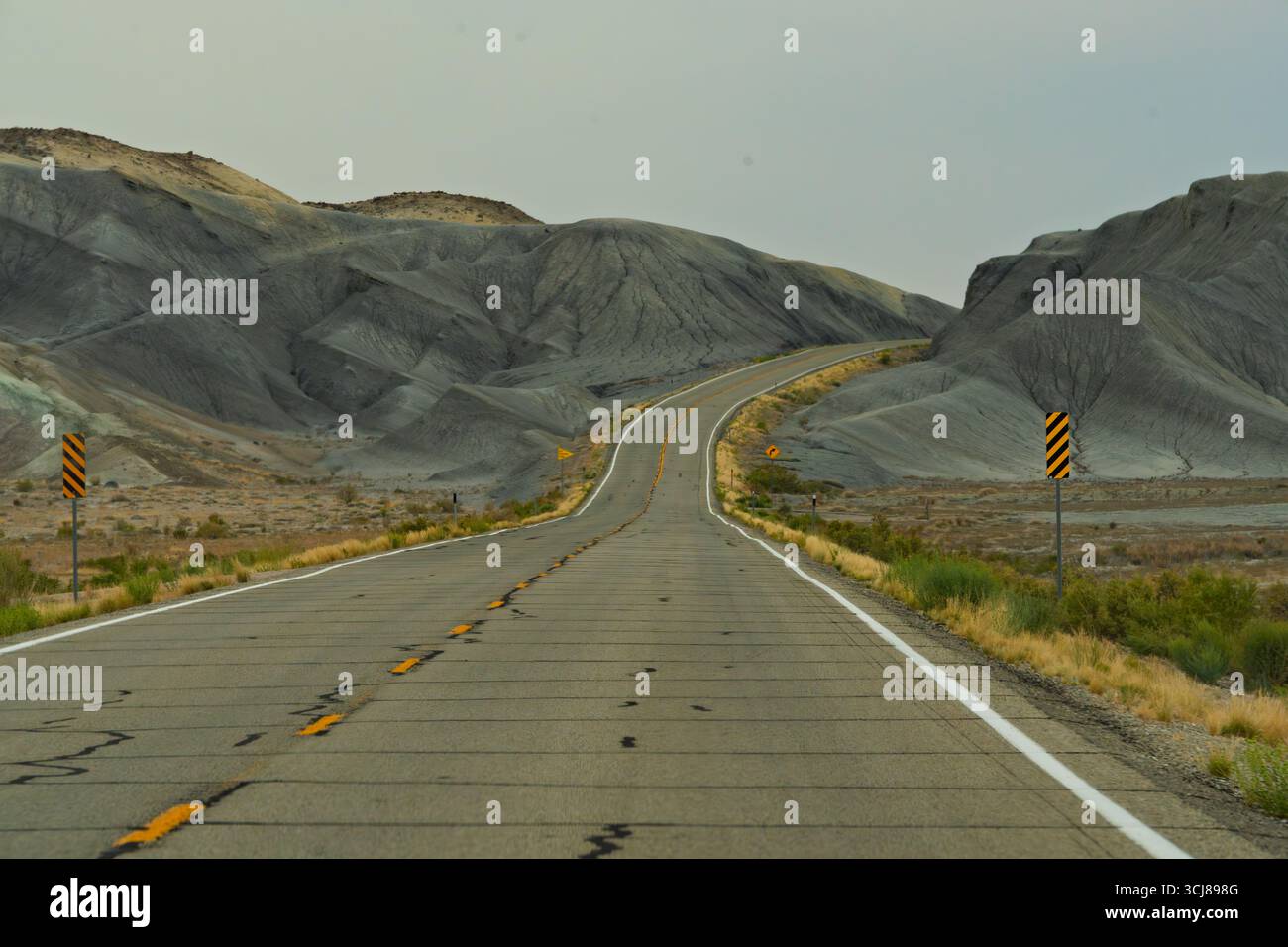 A long, winding asphalt road stretches into the distance, flanked by ...