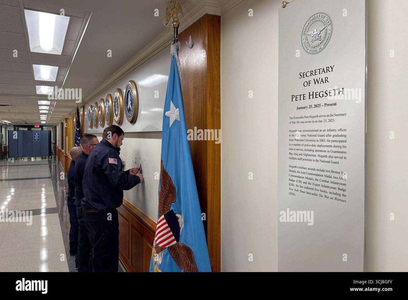Workers remove sign lettering at the Pentagon after President Donald ...