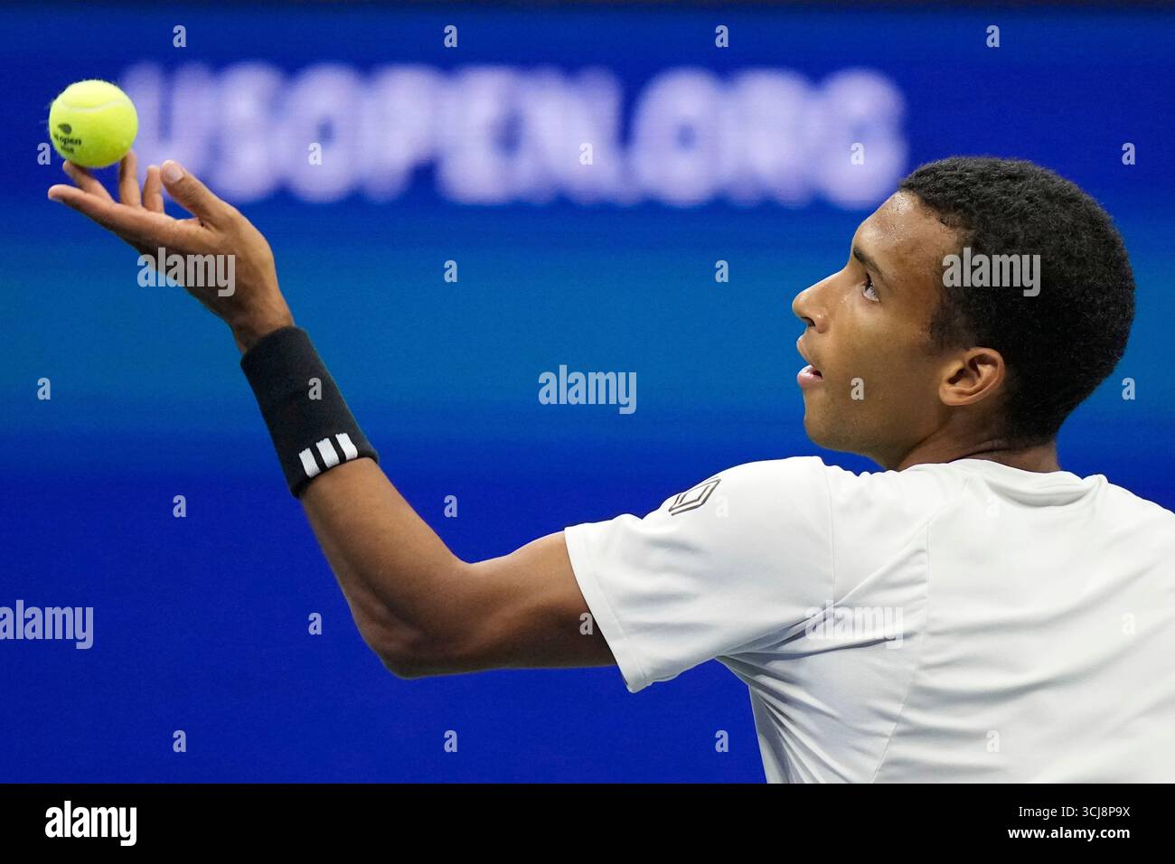 Felix Auger-Aliassime, of Canada, serves to Jannik Sinner, of Italy ...