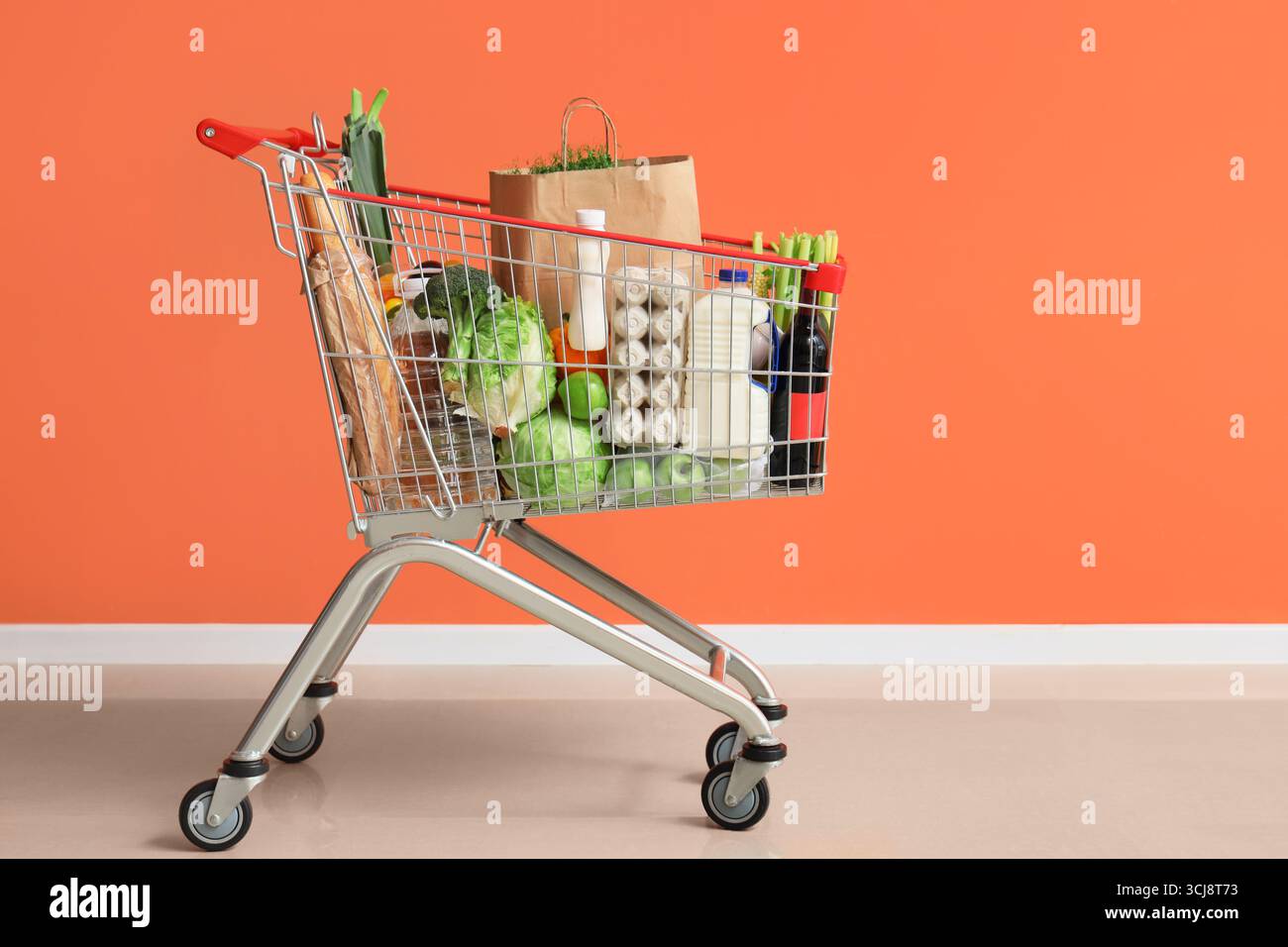 Shopping cart with different fresh products near orange wall Stock ...