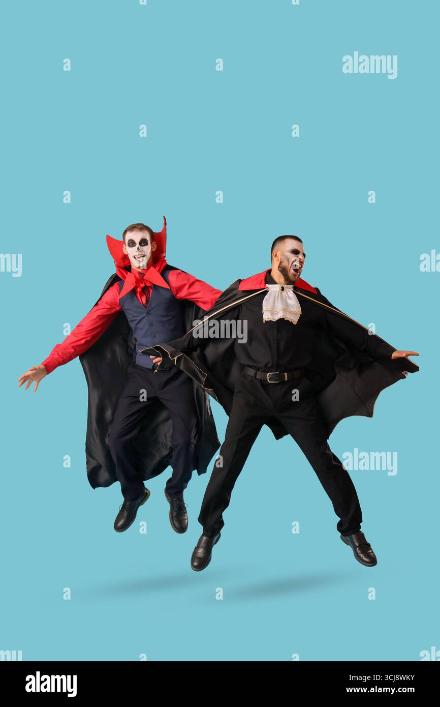 Scary men dressed as vampires for Halloween jumping on blue background ...