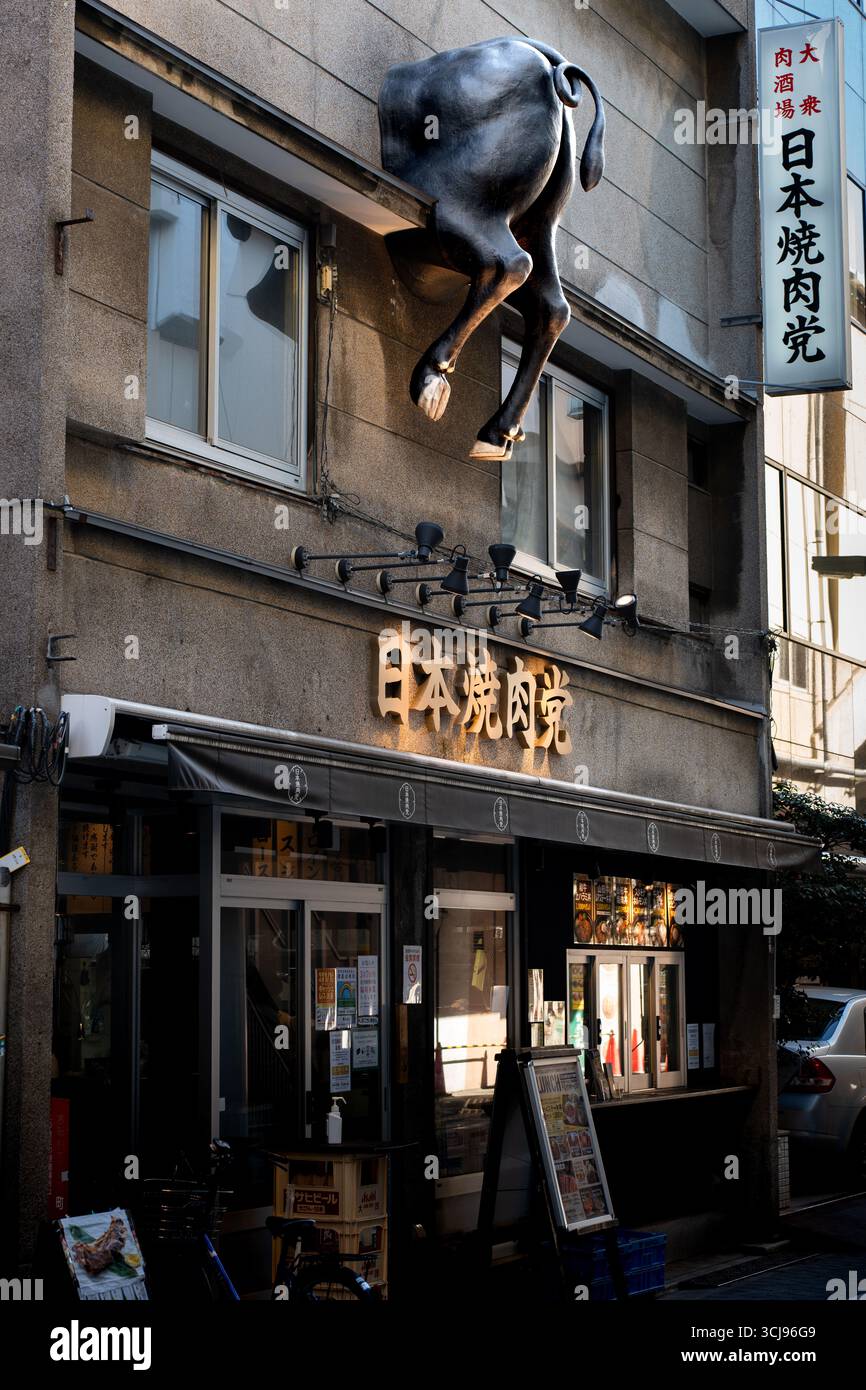 Unique yakiniku restaurant facade with a cow sculpture protruding from ...
