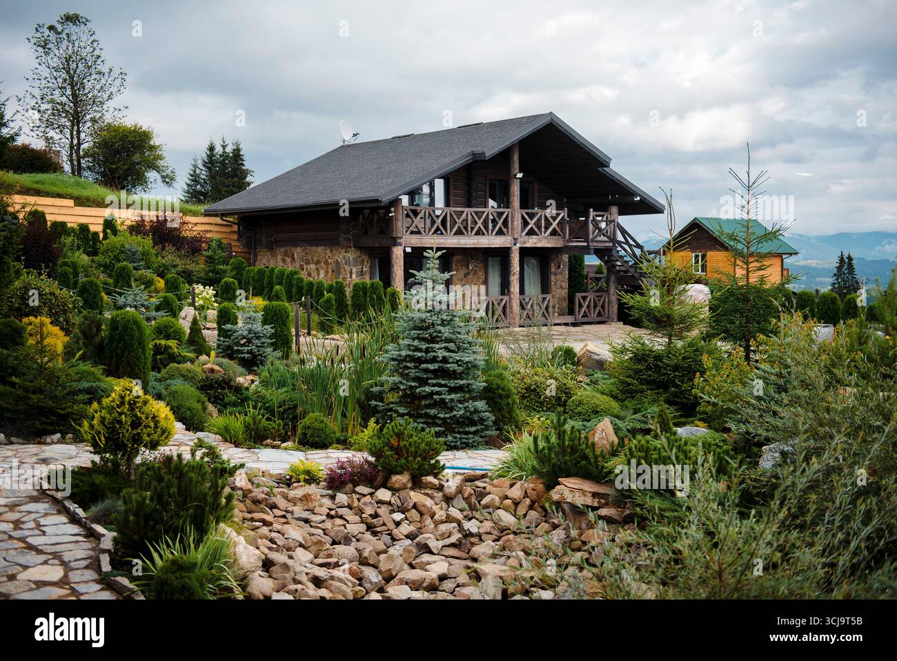 Rustic wooden cabin surrounded by lush garden and stone pathway Stock ...