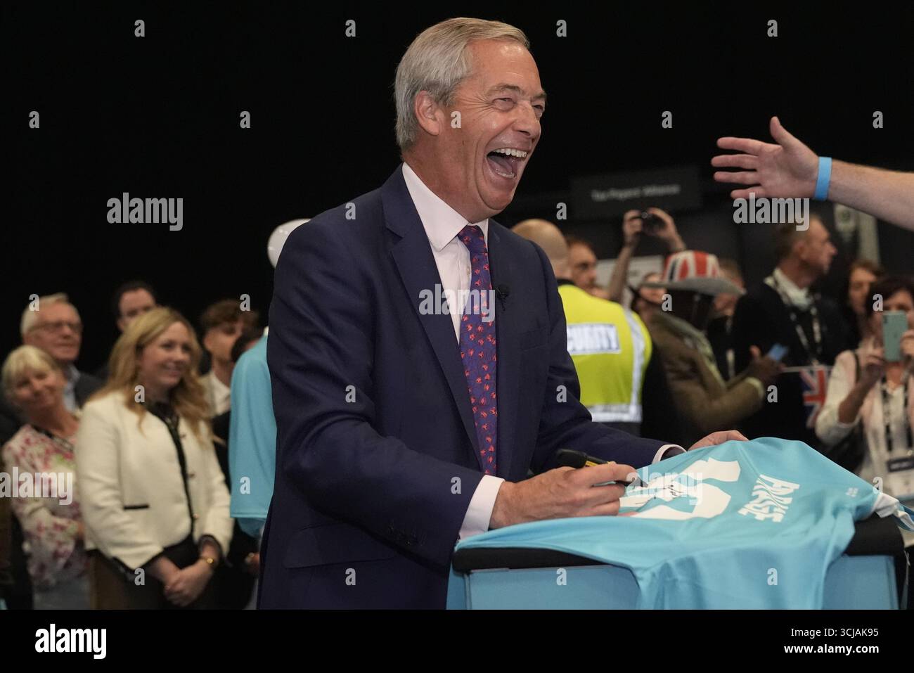 Reform UK leader Nigel Farage signing a football shirt during the party ...