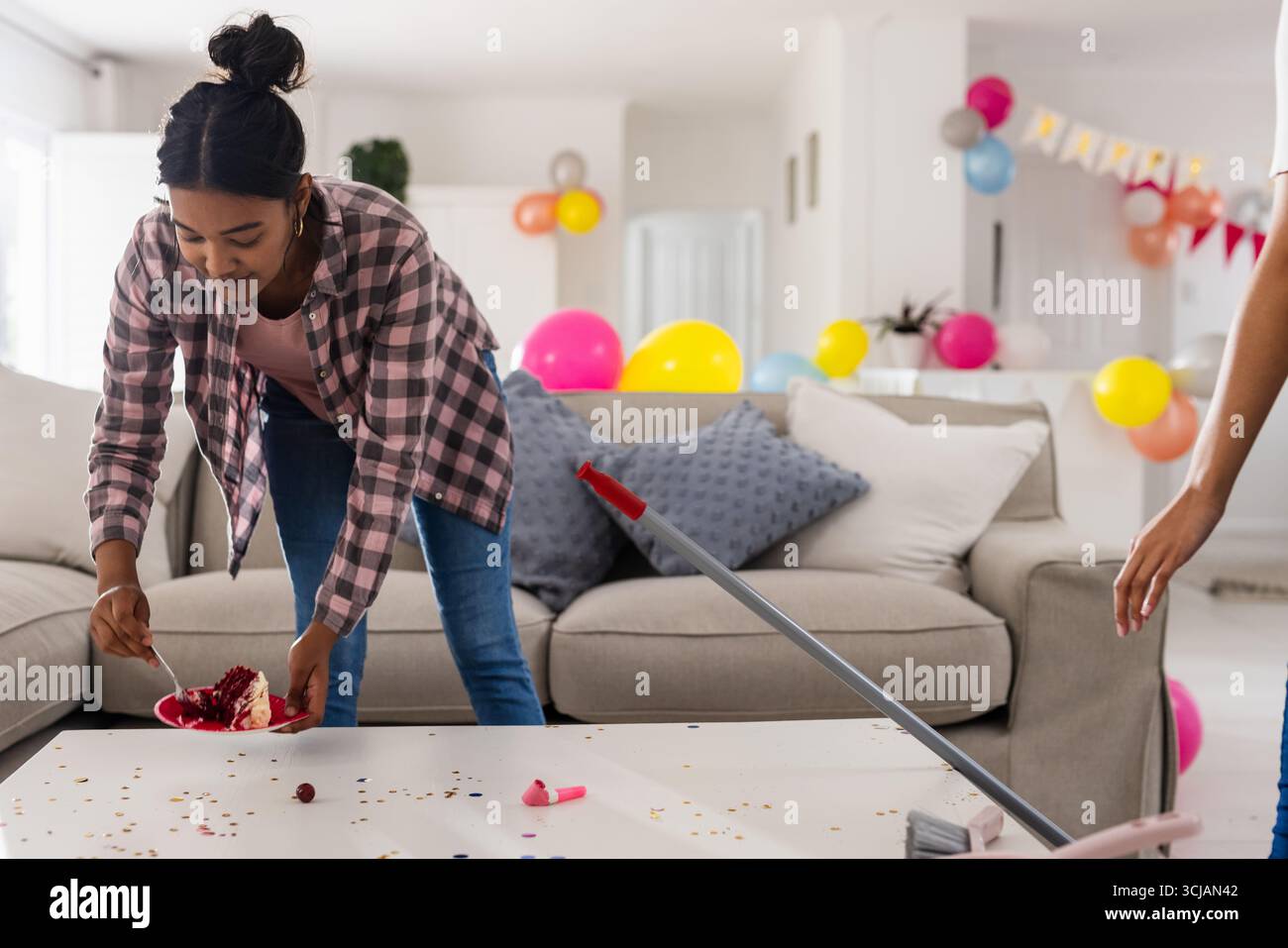 Cleaning up after party, woman tidying living room with balloons and ...