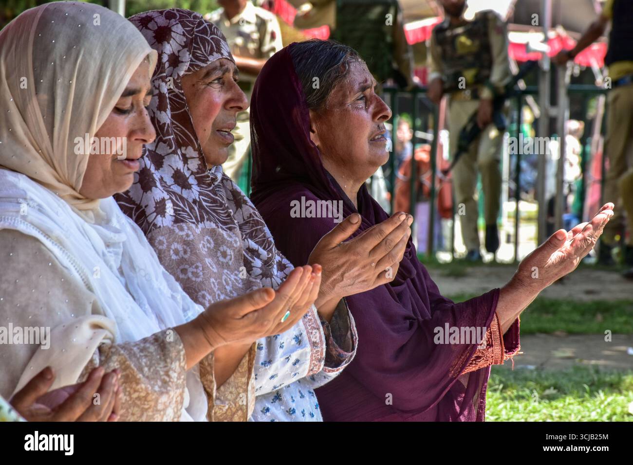 A paramilitary trooper stands guard as Kashmiri Muslim devotees pray on ...
