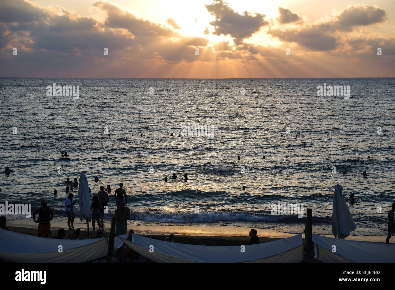 Syrian bathers swim as the sun sets at a beach resort in Wadi Qandil ...