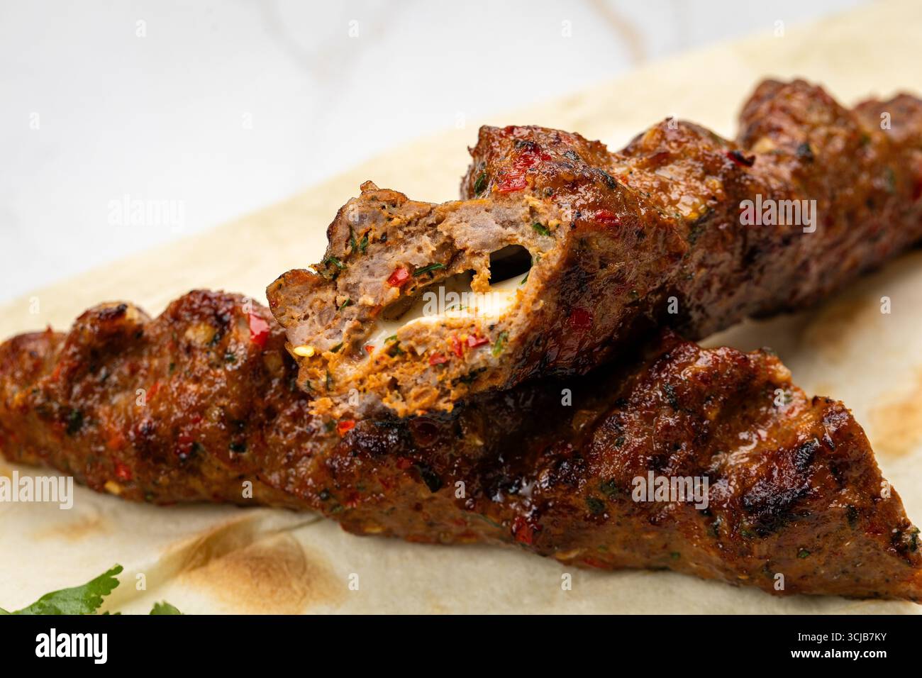 Close-up of grilled kebab with melted cheese inside on flatbread, juicy ...