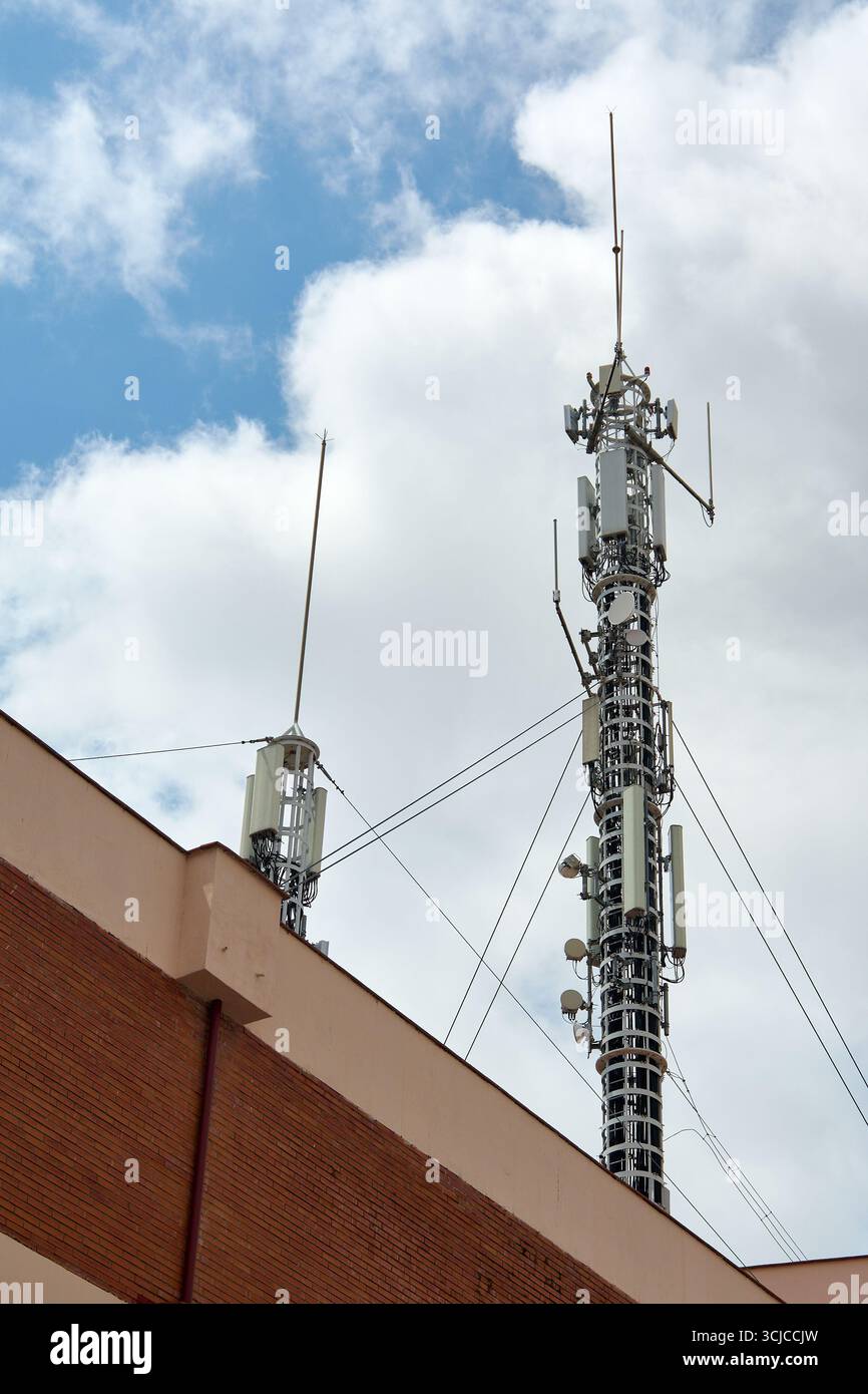 A vertical shot of two mobile communication towers on a rooftop ...