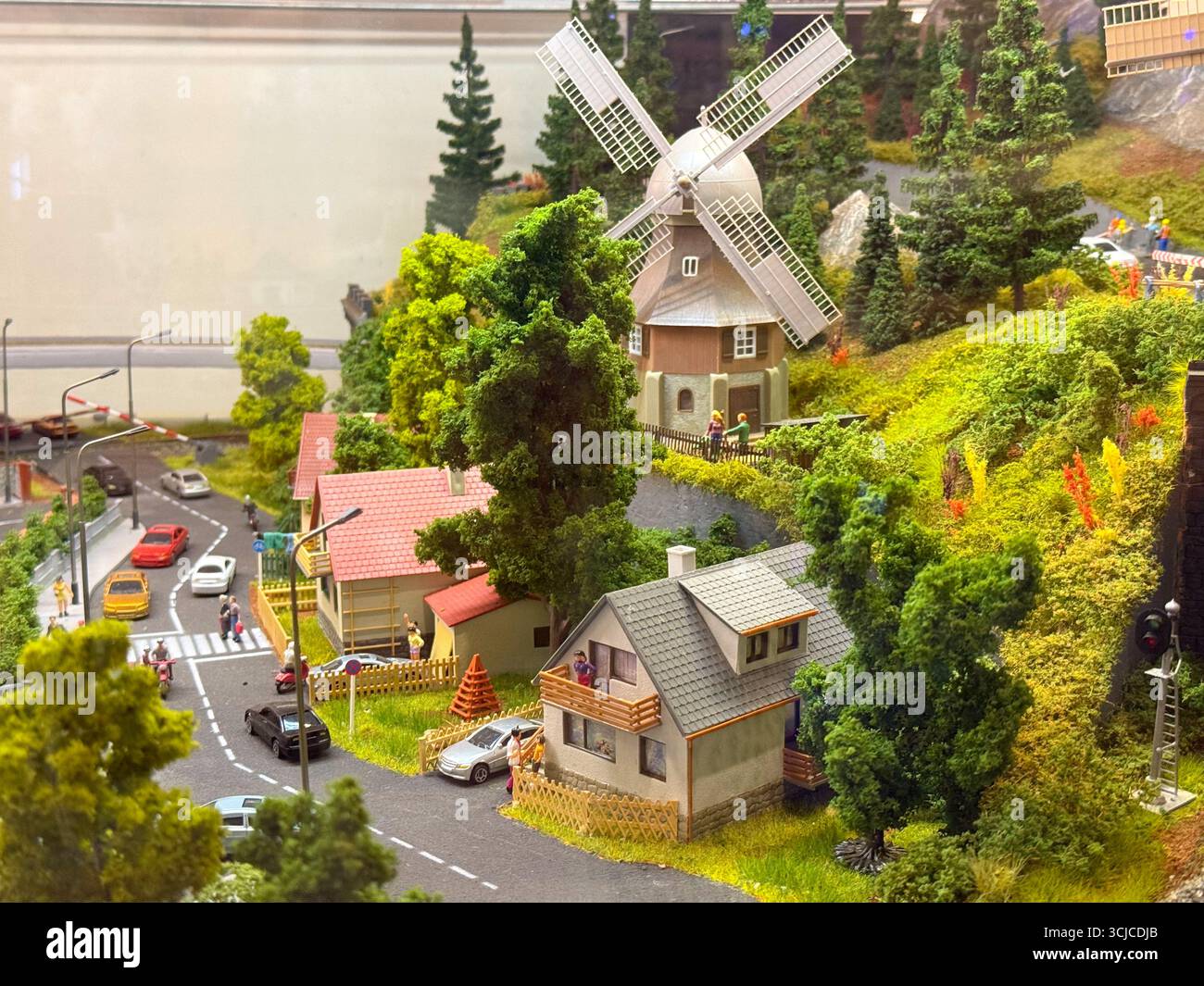 A miniature model shows suburban houses, cars, and people on streets ...