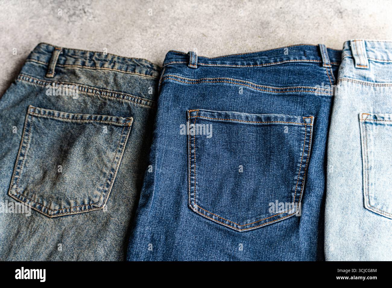 Three pairs of jeans in different washes lined up side by side on a ...