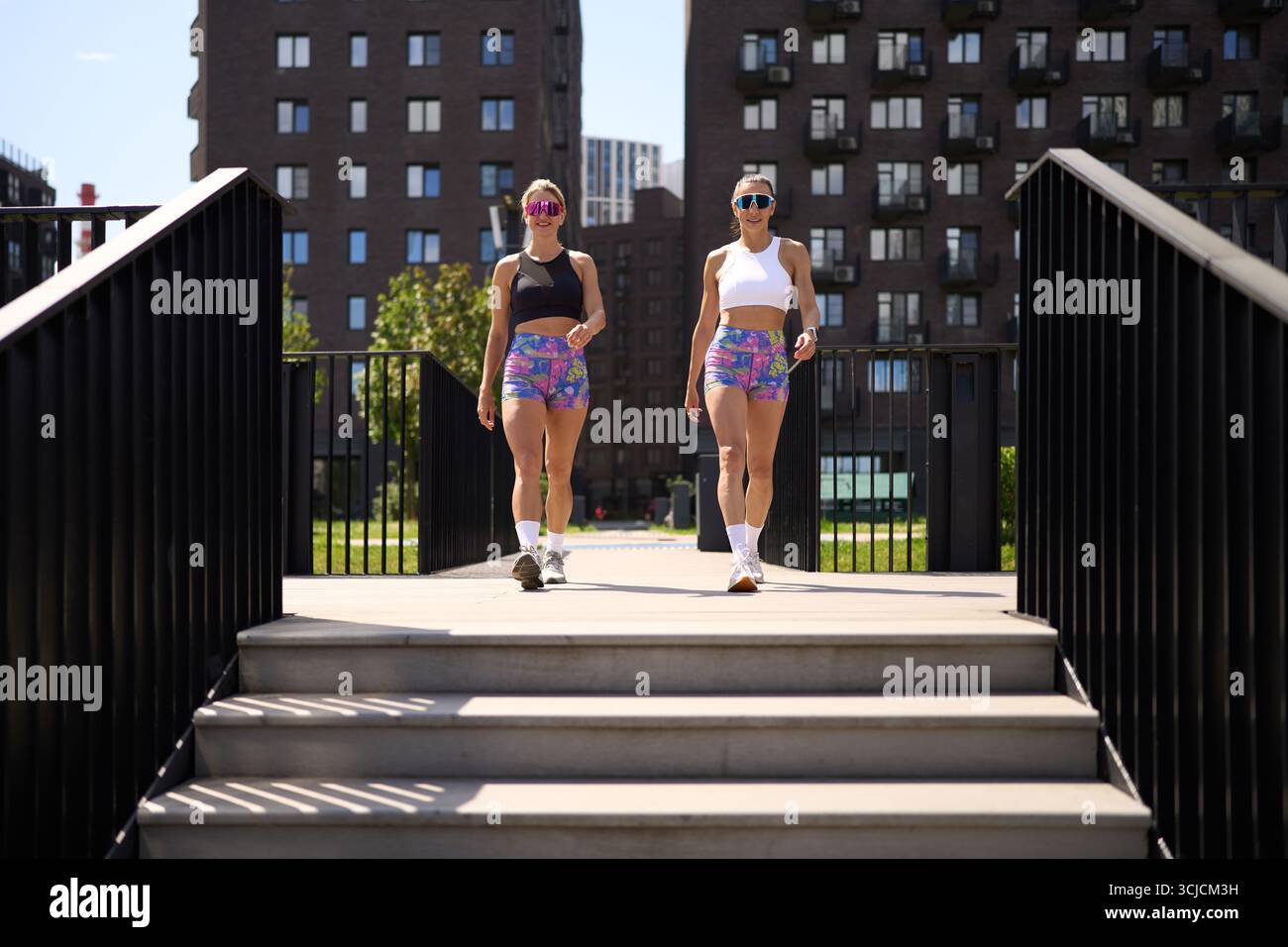 Two women jog through a vibrant cityscape, enjoying a sunny day and ...