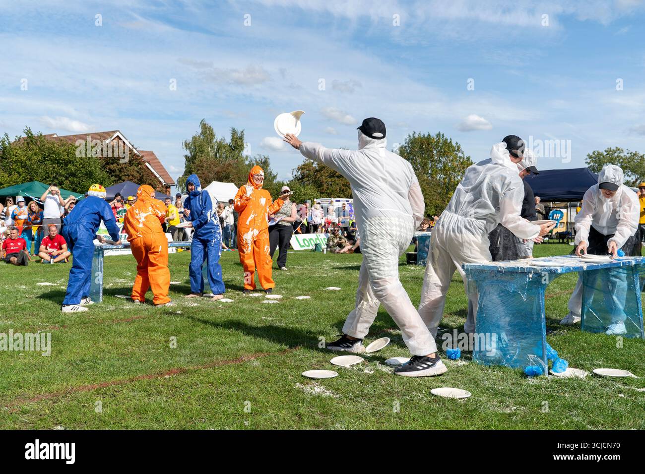 Two teams of four people in fancy dress throwing custard pies at each ...