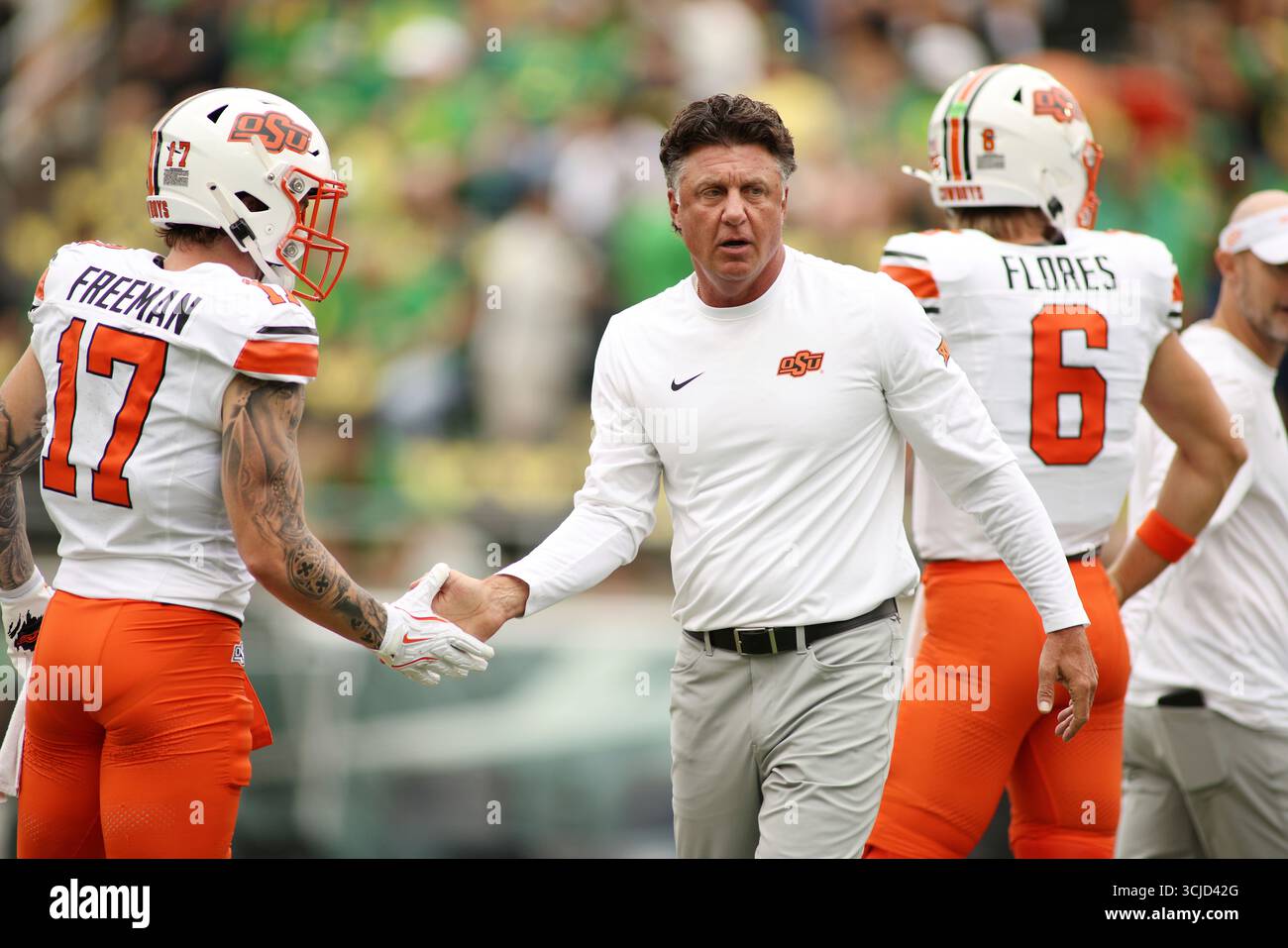 Oklahoma State head coach Mike Gundy slaps hands with wide receiver Gavin Freeman (17) during ...