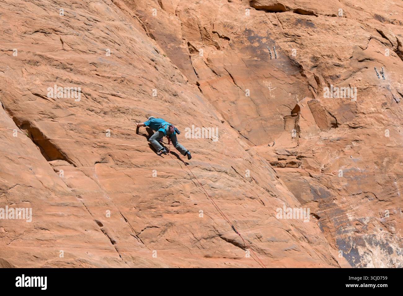 Moab, Utah, USA - 25 May 2025: Person climbing a sheer rock face using ...