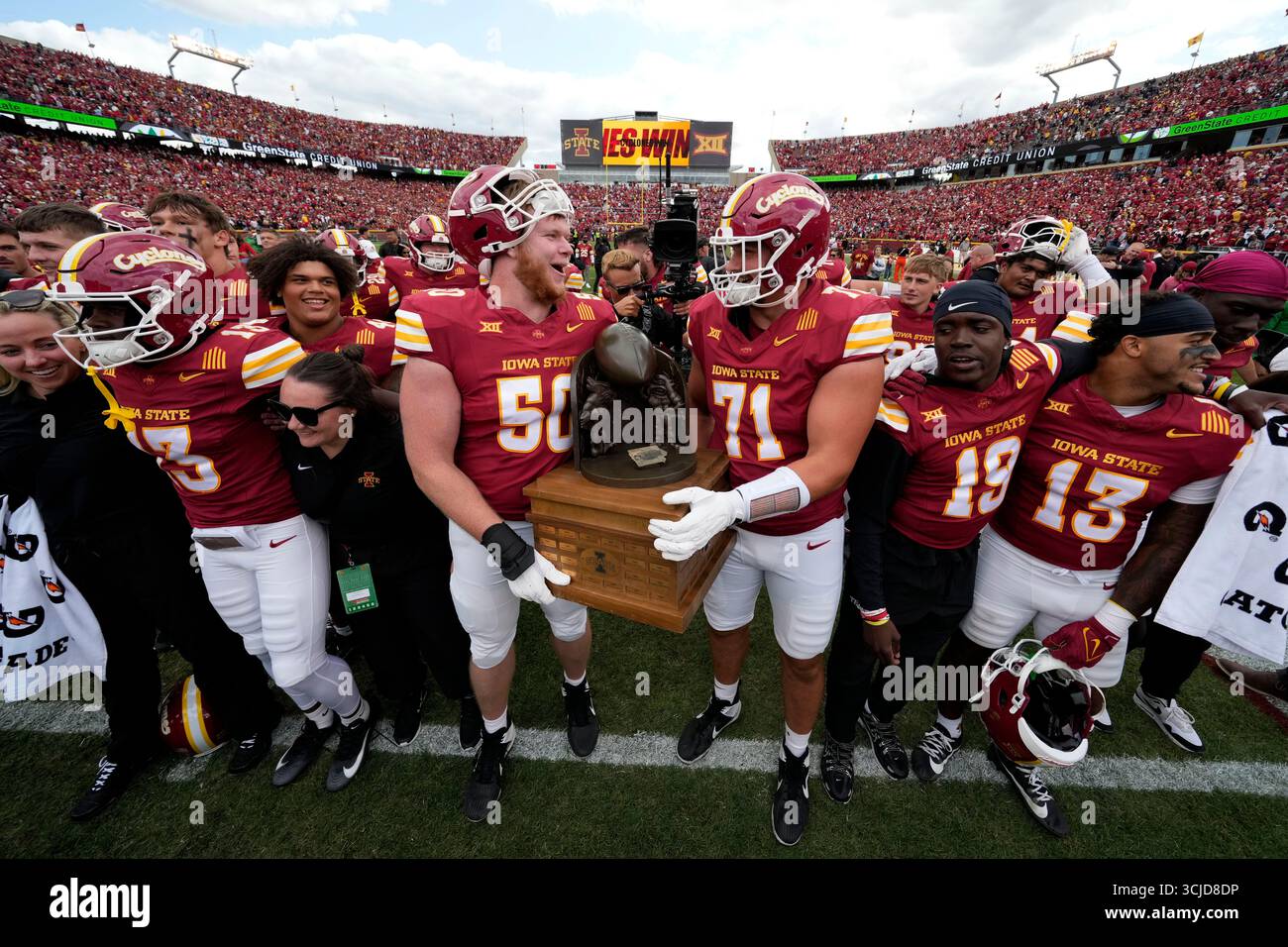 Iowa State players celebrate with the Cy-Hawk trophy after an NCAA ...