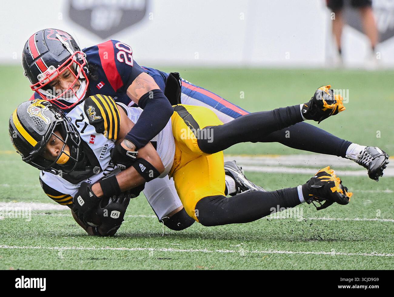 Hamilton Tiger-Cats' Tim White (12) hangs onto the ball as he's tackled ...