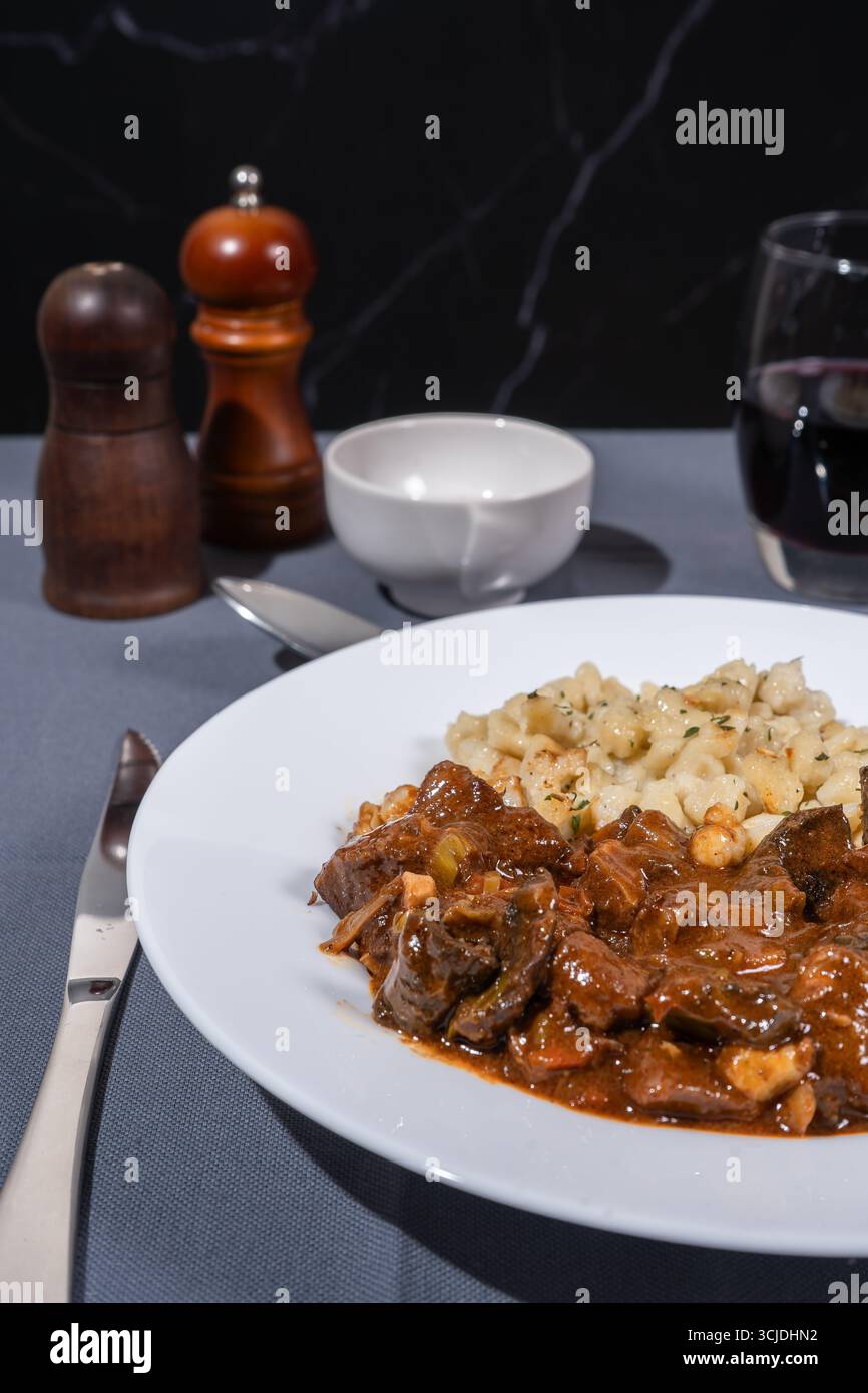 Hungarian goulash with spaetzle served on a white plate, accompanied by ...