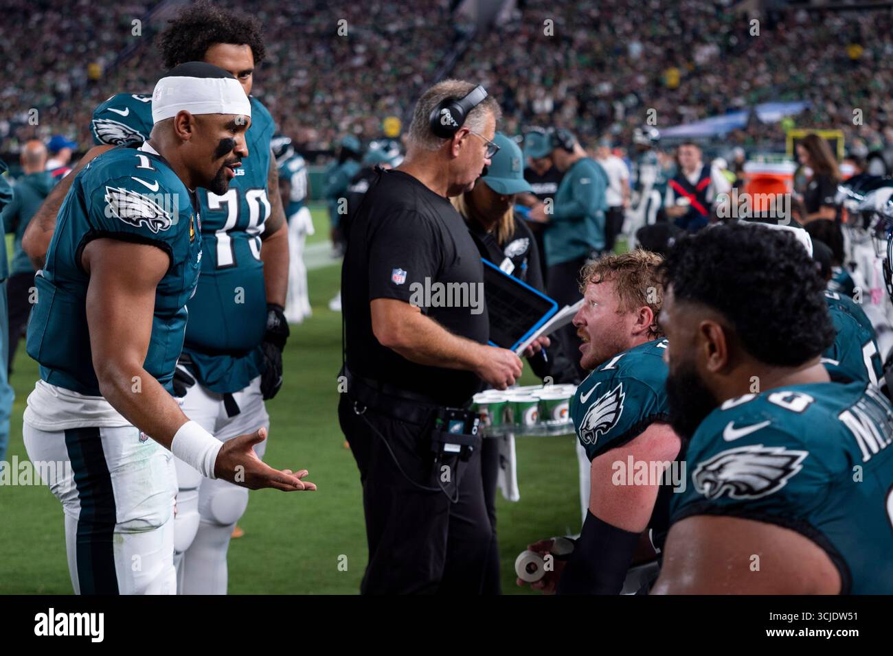 Philadelphia Eagles quarterback Jalen Hurts, left, talking things over with center Cam Jurgens ...