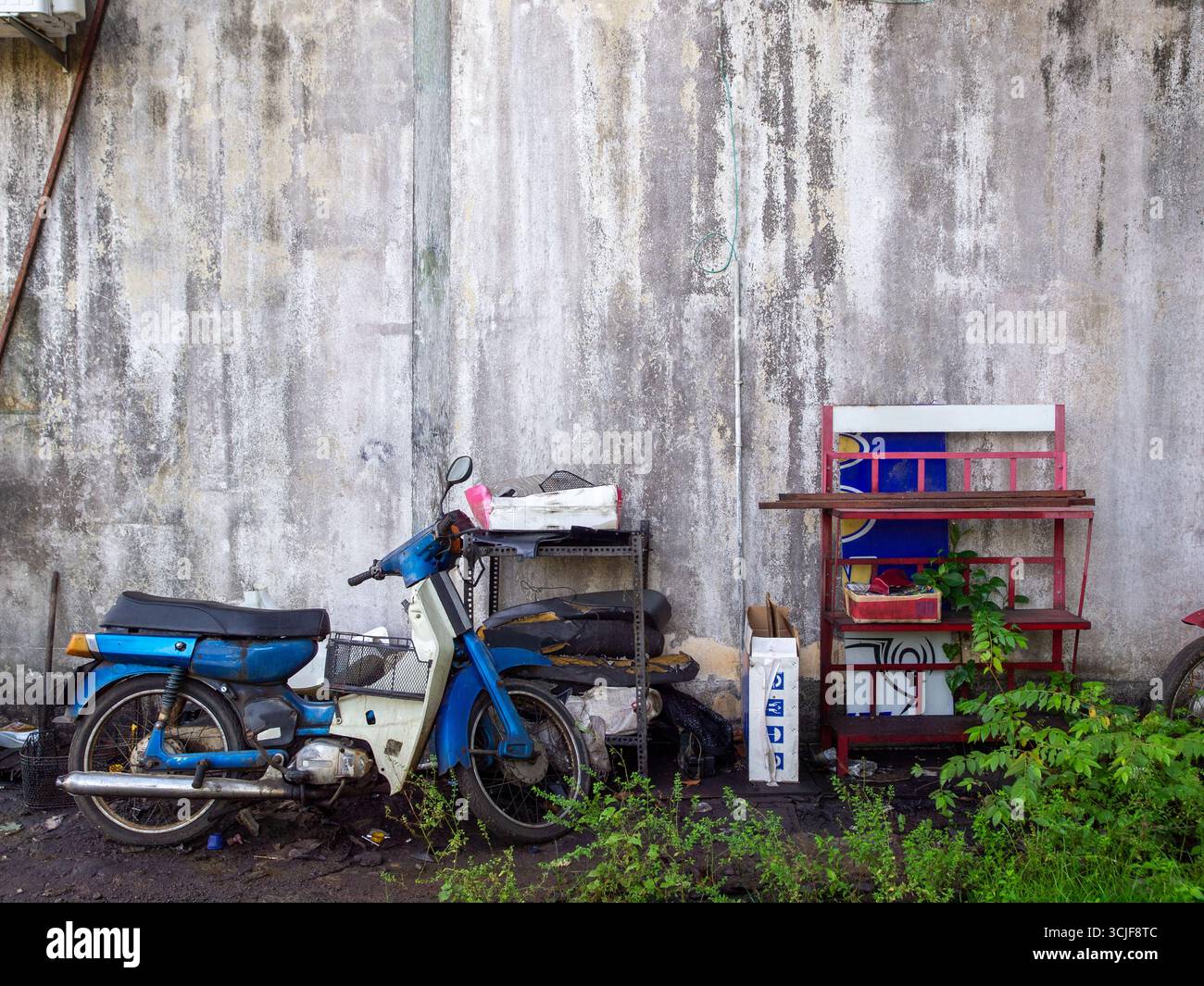 Stained white walls with an old motorcycle, damaged seats, steel racks ...