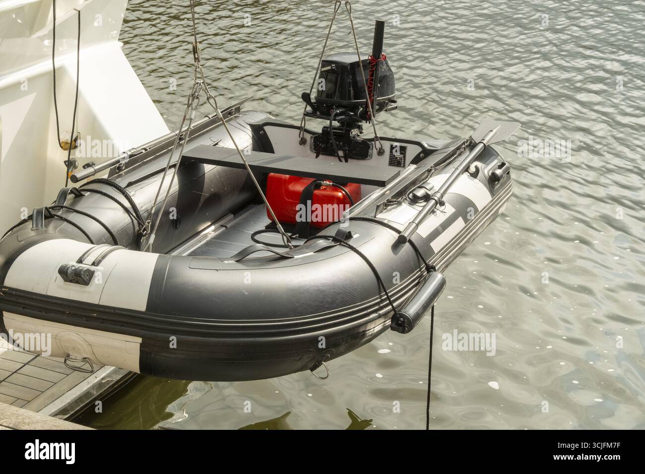Inflatable dinghy with outboard motor hanging from davit crane system ...
