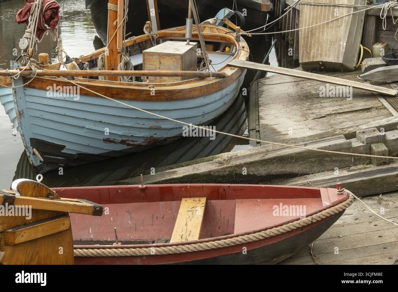 Two charming wooden boats rest peacefully at a weathered pier, evoking ...