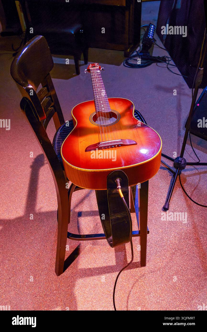 Image of an acoustic guitar lying on a chair that stands on the stage ...