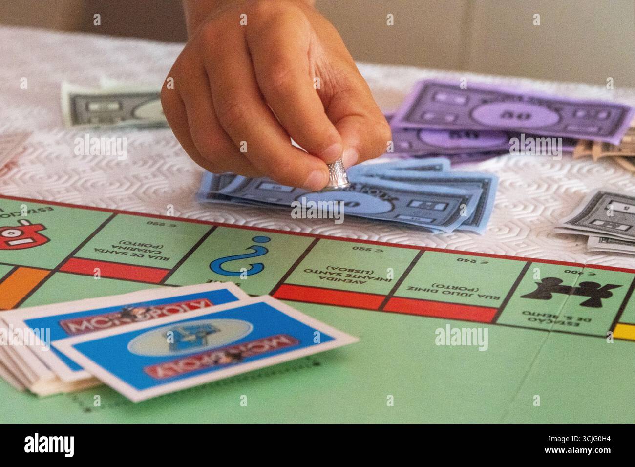Kid is playing monopoly board game, moving the metal thimble and ...