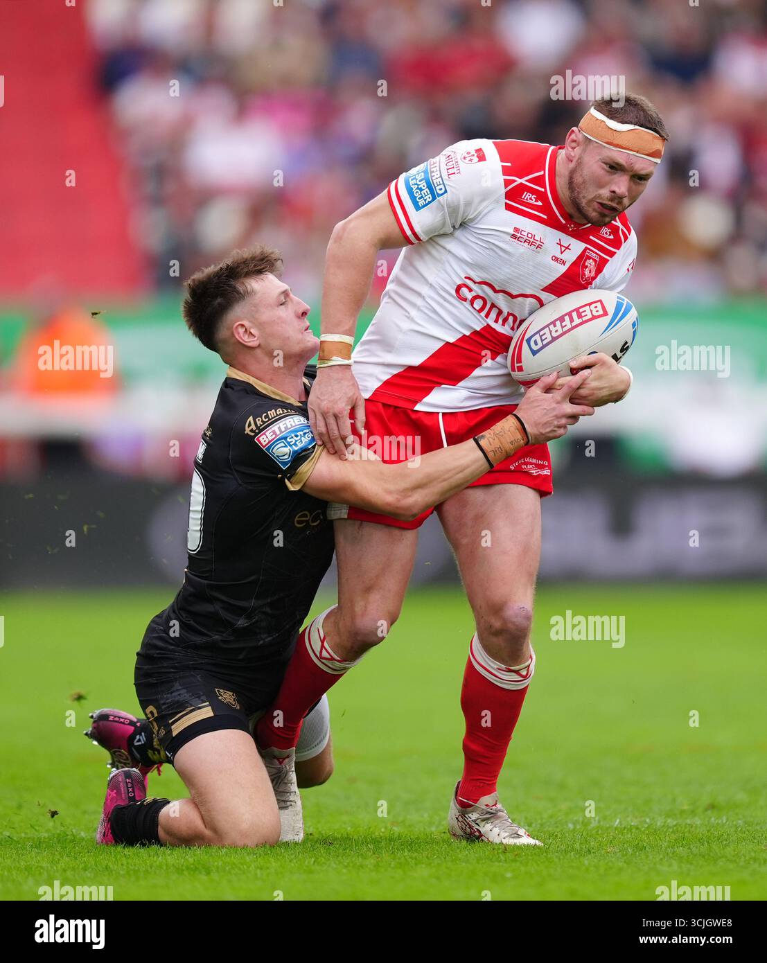 Hull KR's James Batchelor is tackled by Hull FC's Davy Litten during ...