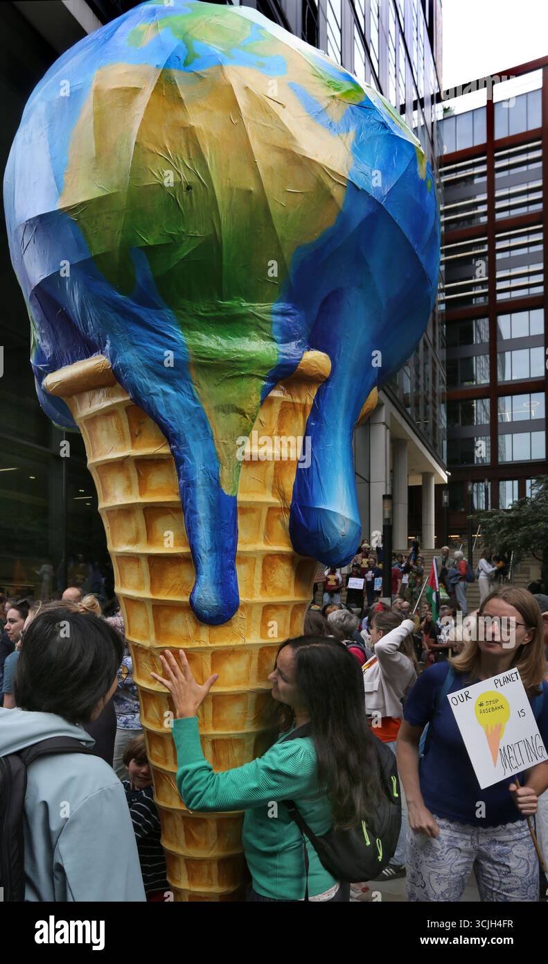 Protesters gather together around a large model ice cream cone with a ...