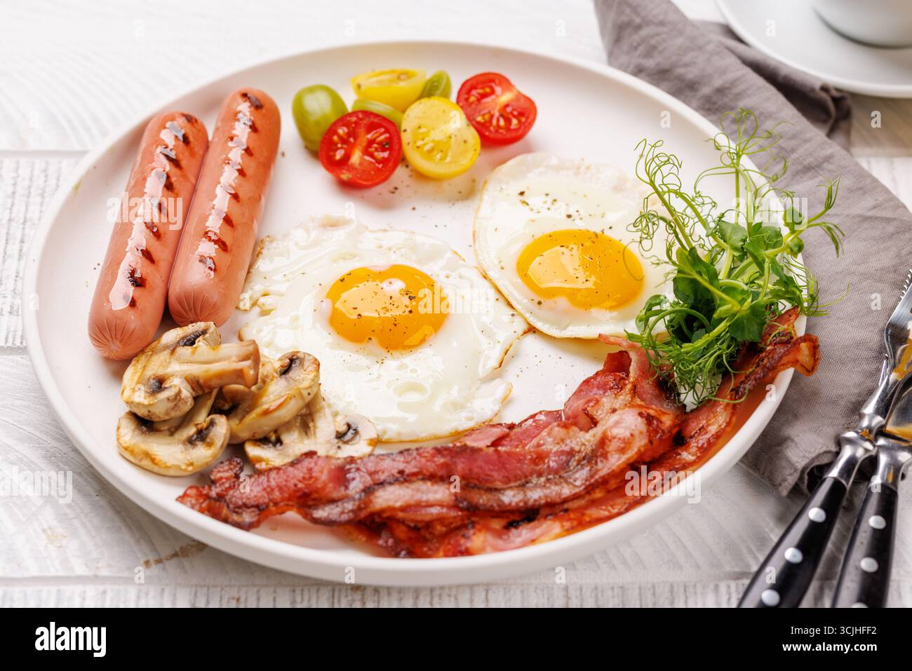 A classic breakfast plate featuring sunny-side-up eggs, crispy bacon ...
