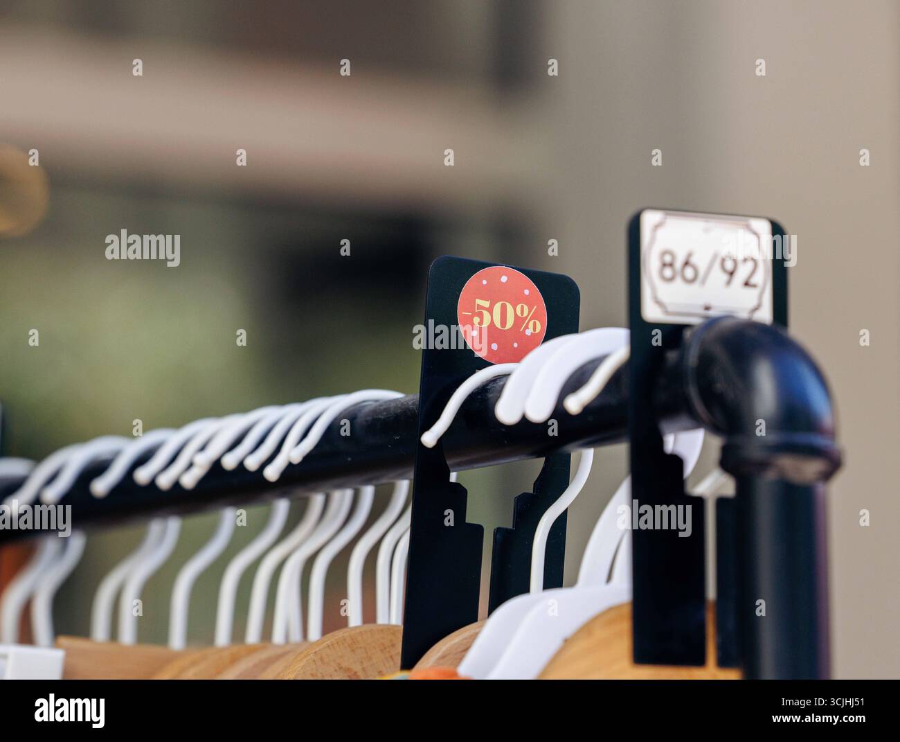 Clothing rack with 50% discount sign and size indicator on hangers ...