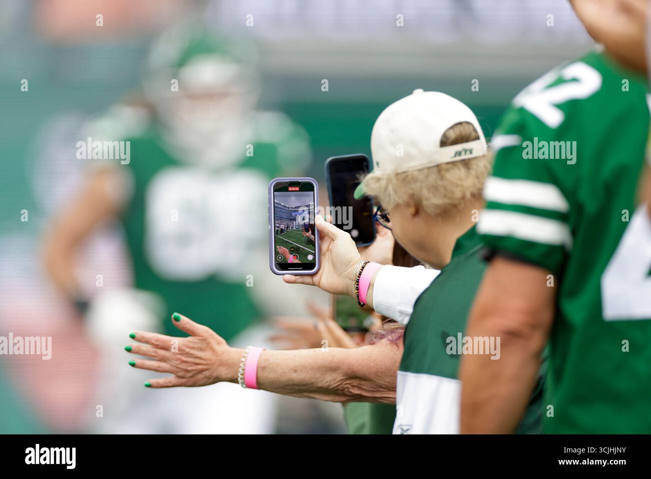 A spectator uses a cell phone to capture video of New York Jets players ...