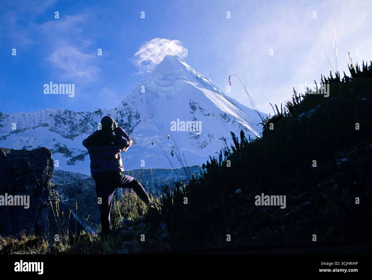 Using binoculars a single male mountain climber looks at Artesonraju 6 ...