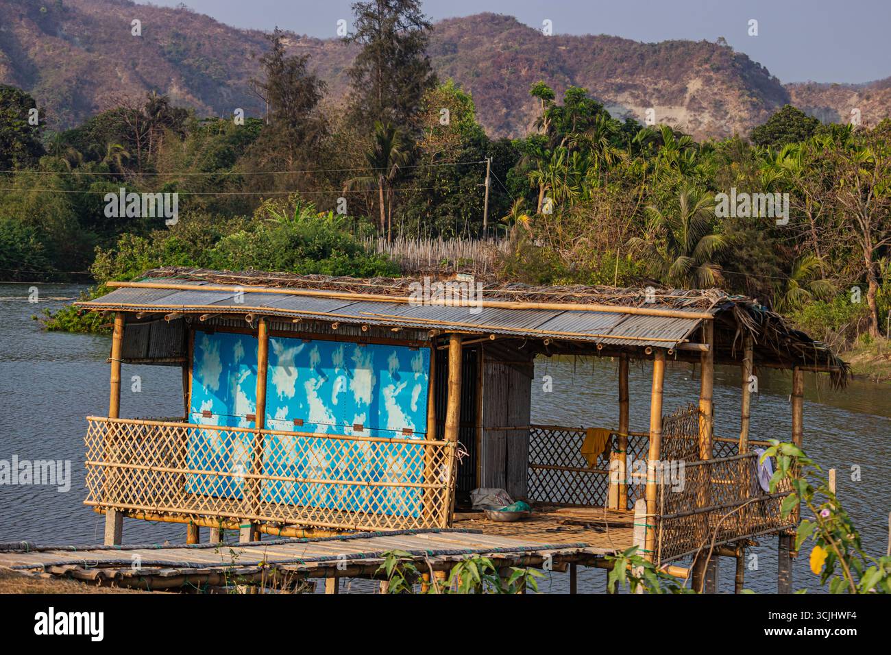 Rustic bamboo hut standing over calm river water with green tropical ...