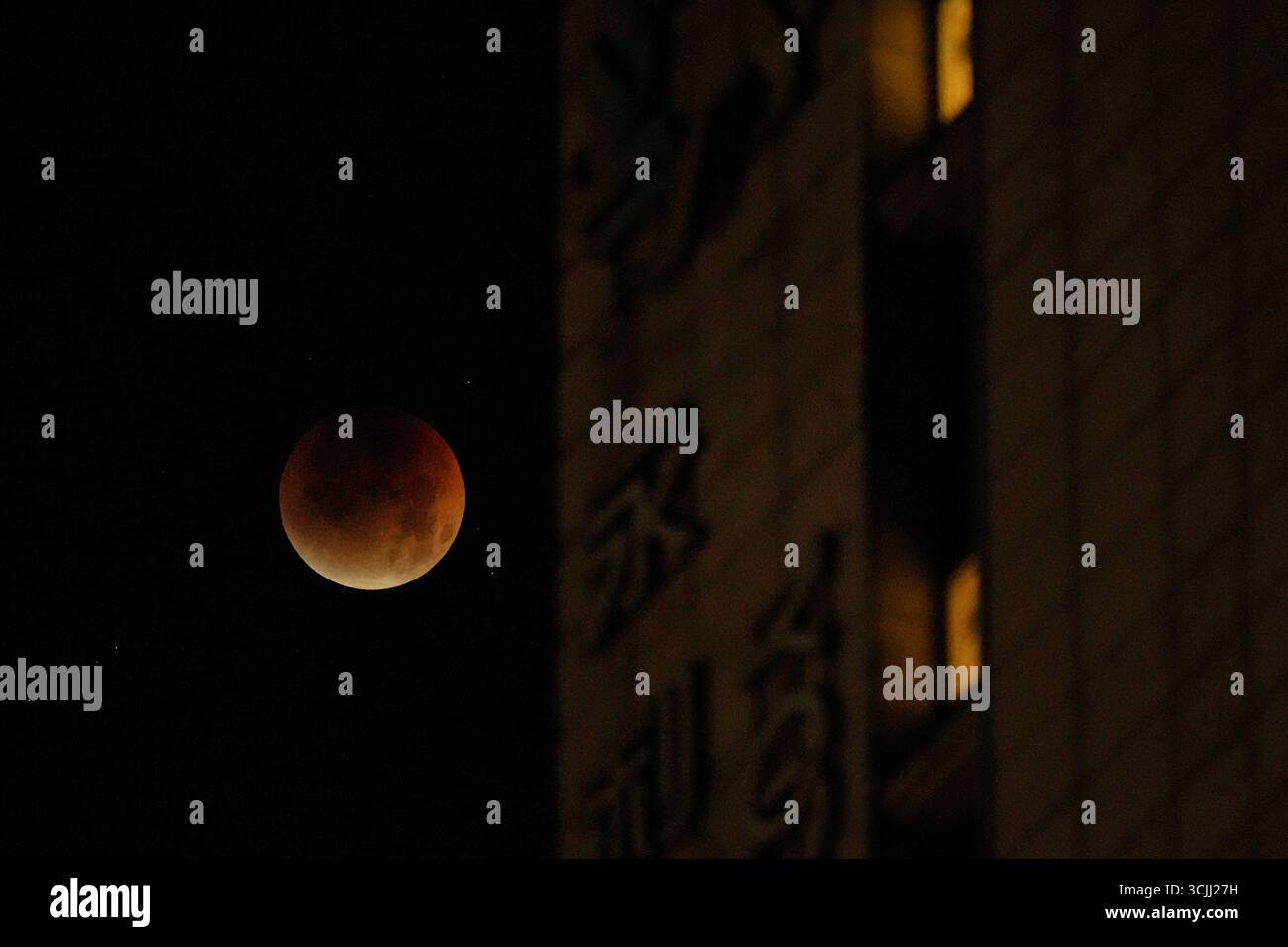 A total lunar eclipse, known as the blood moon, is visible beside a ...