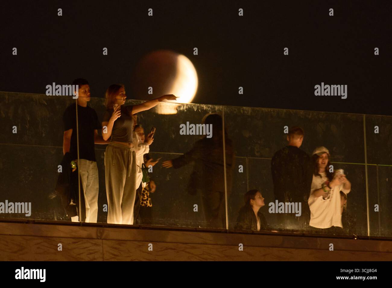 A partial lunar eclipse is seen over the Floating Bridge as people ...