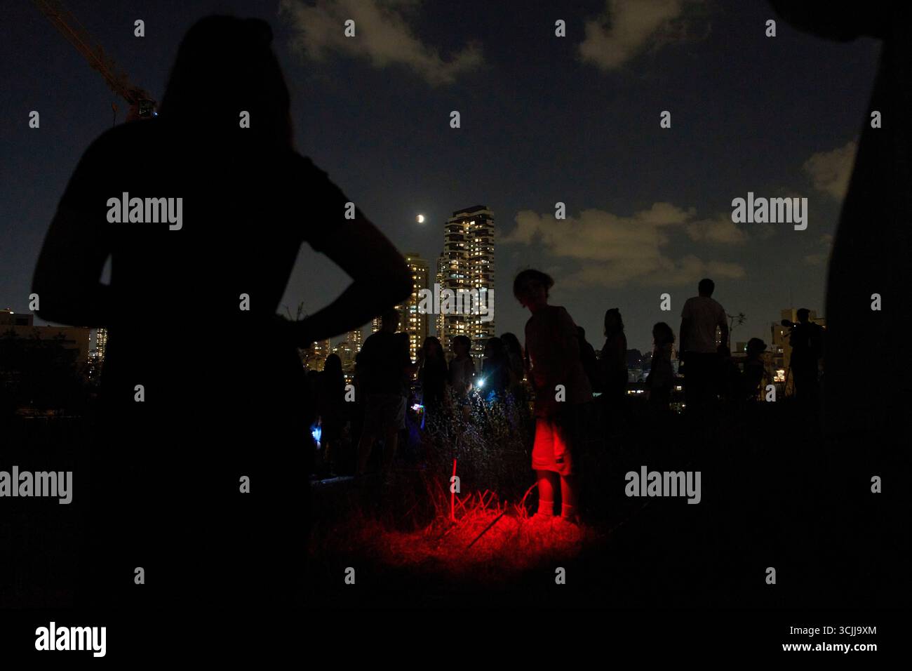 People gather to watch a total lunar eclipse, known as the blood moon, in Tel Aviv, Israel ...