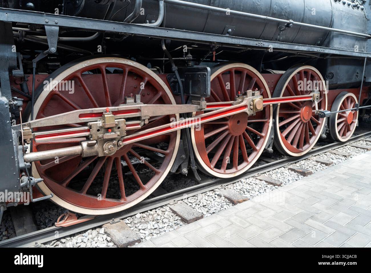 Close-up view of steam locomotive wheels and mechanical drive rods ...