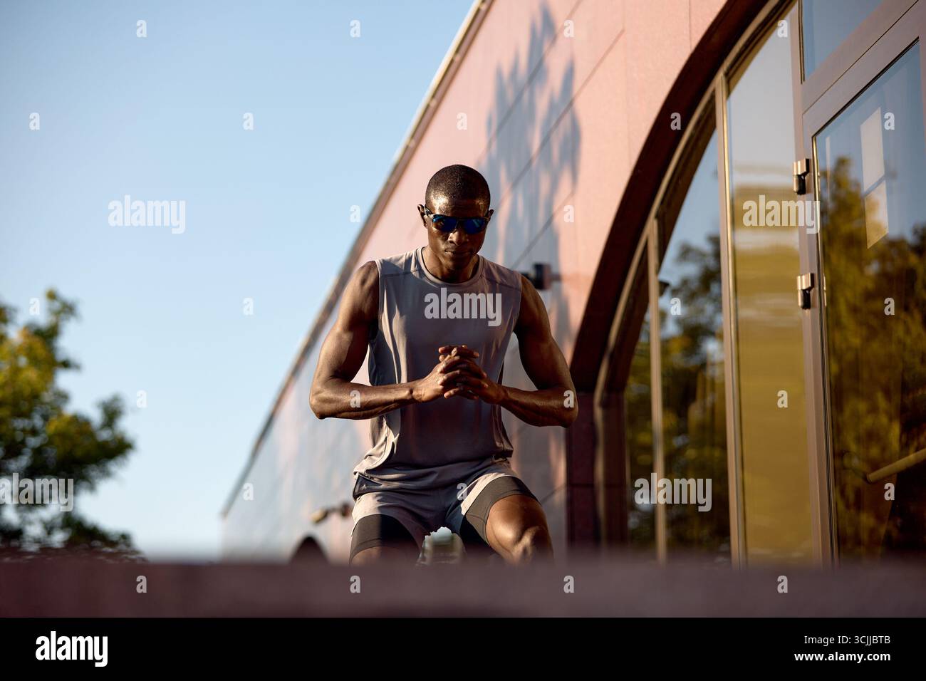 A fit man engaged in a focused exercise session outdoors, dressed in ...