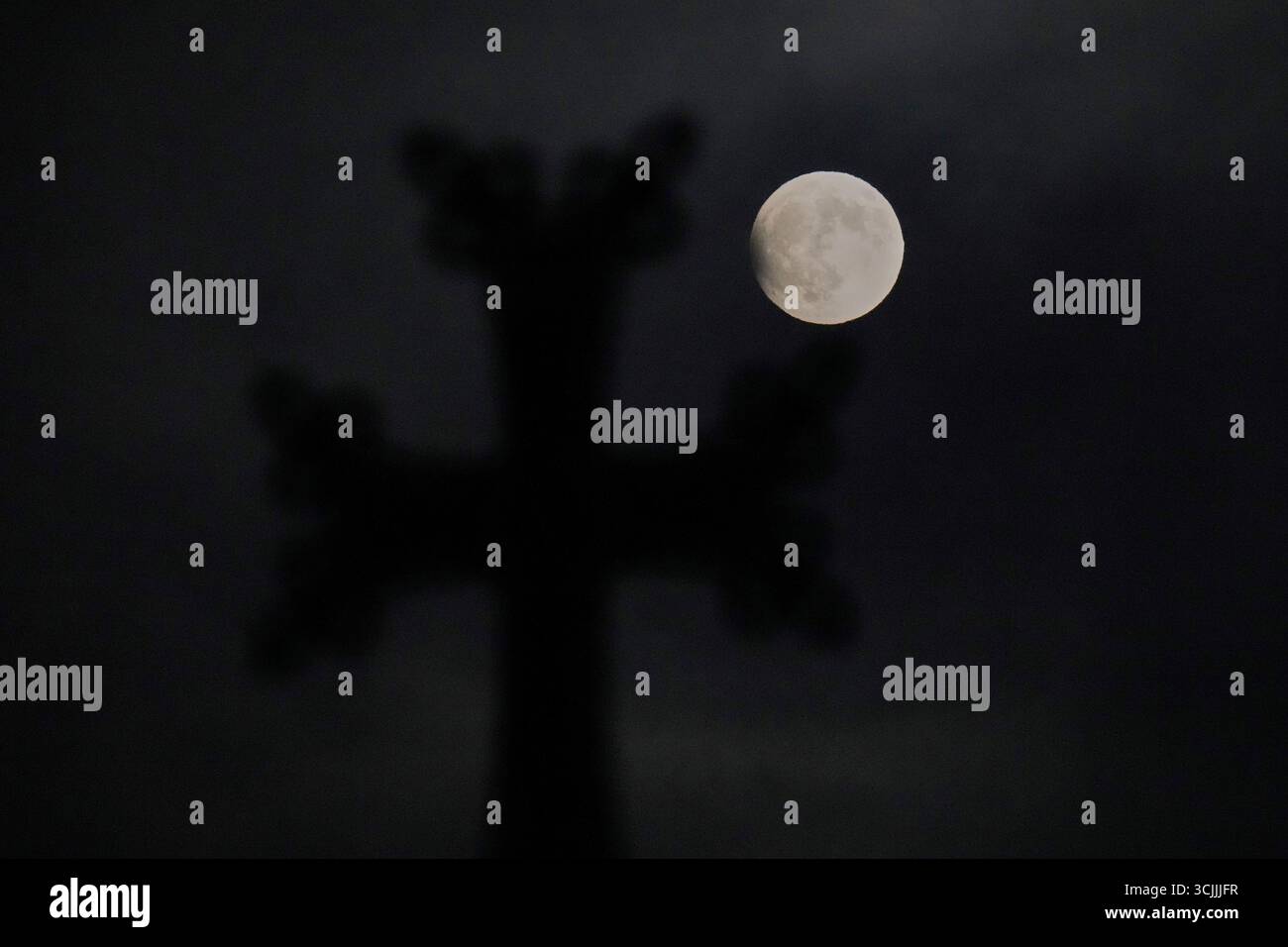 The moon is seen during a total lunar eclipse behind a cross over ...