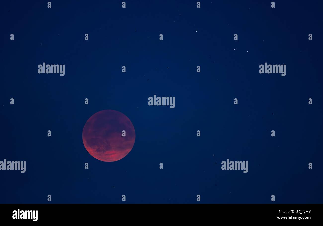Red total lunar eclipse glowing in the dark night sky with visible ...