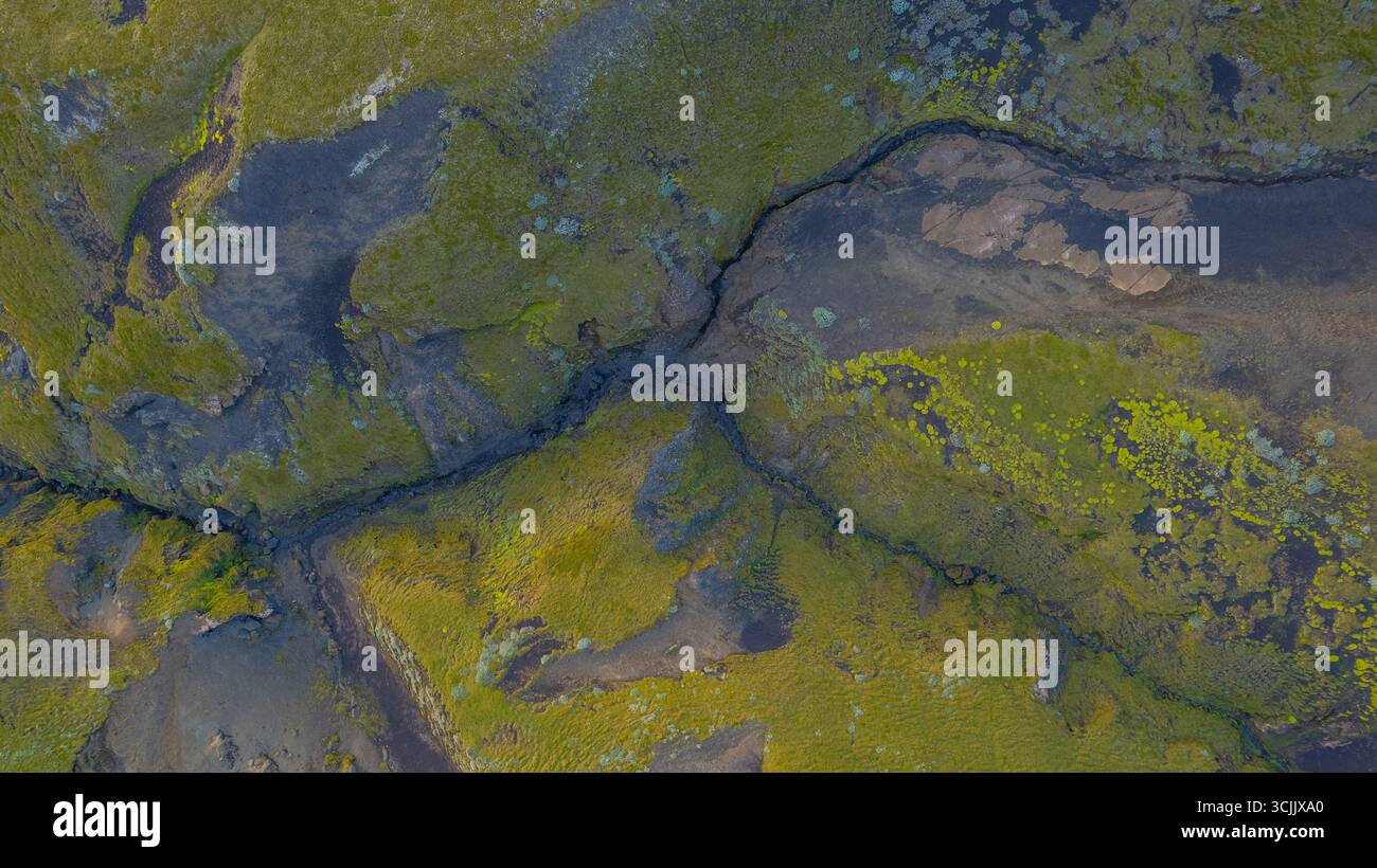 Top down aerial of green moss wetlands in Iceland with dark volcanic ...
