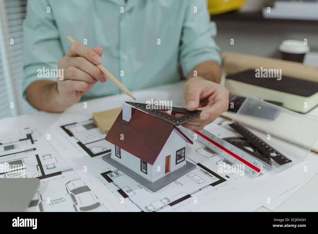 An architect uses a triangular ruler and pencil to measure a house ...