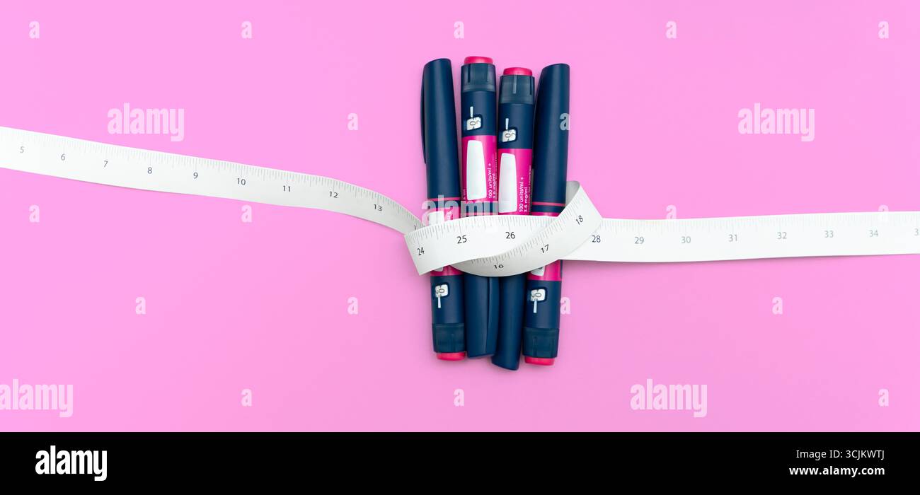 Insulin injection pens tied with measuring tape on pink background ...