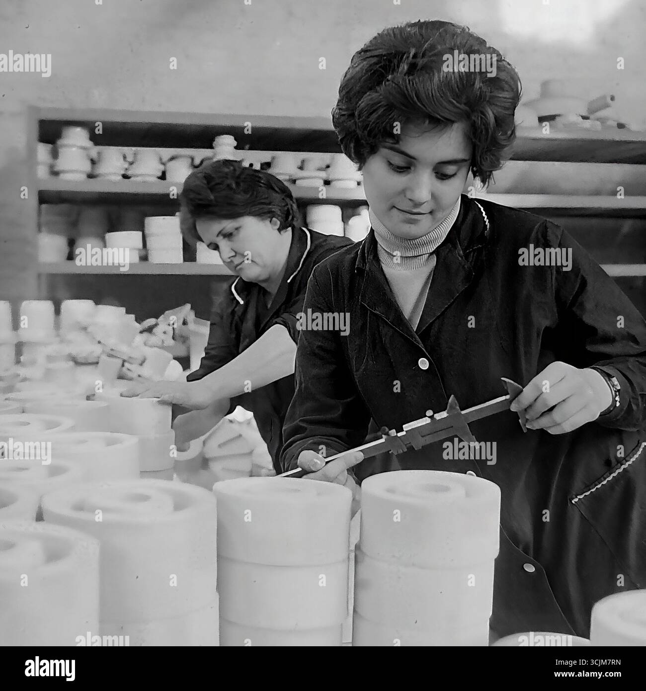 A young female worker with a fashionable 70s hairstyle in a technical ...
