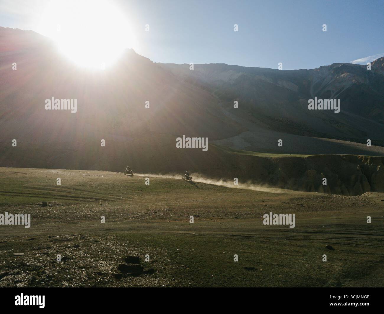 Aerial view of the sun blazing over the stark mountains, casting long ...