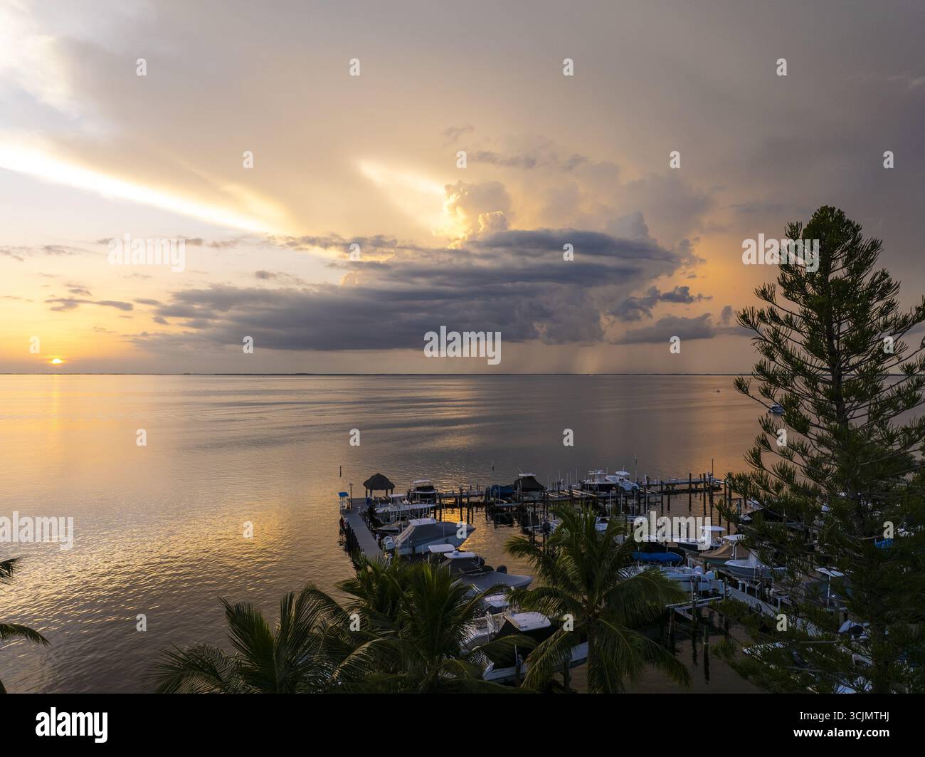 Aerial view of a tranquil harbor reflecting the golden sunset beneath ...