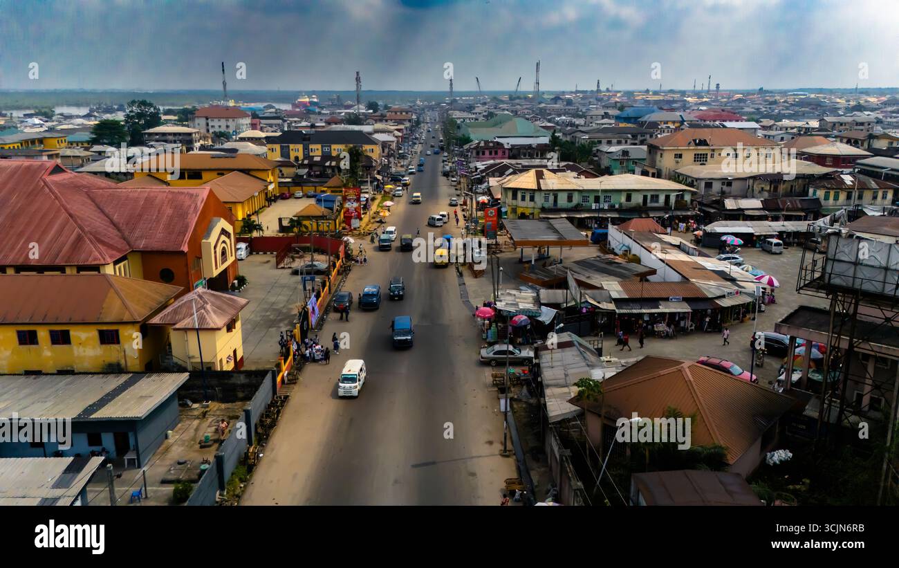 Aerial view of vehicles flow along a wide road lined with buildings of ...
